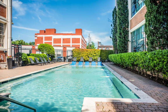 a swimming pool with lounge chairs and a building in the background