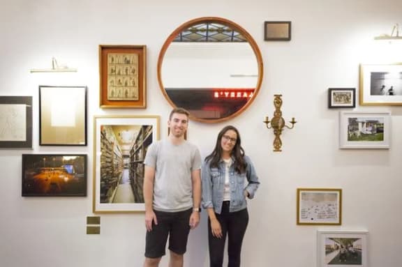 a man and a woman standing in front of pictures on a wall
