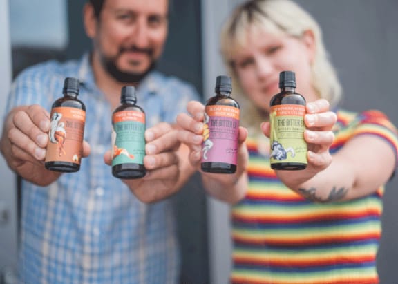 two people holding three bottles of sauce holding their hands