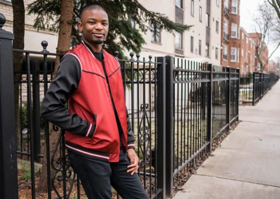 a man in a red jacket standing next to a fence