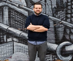 a man standing in front of a graffiti covered wall
